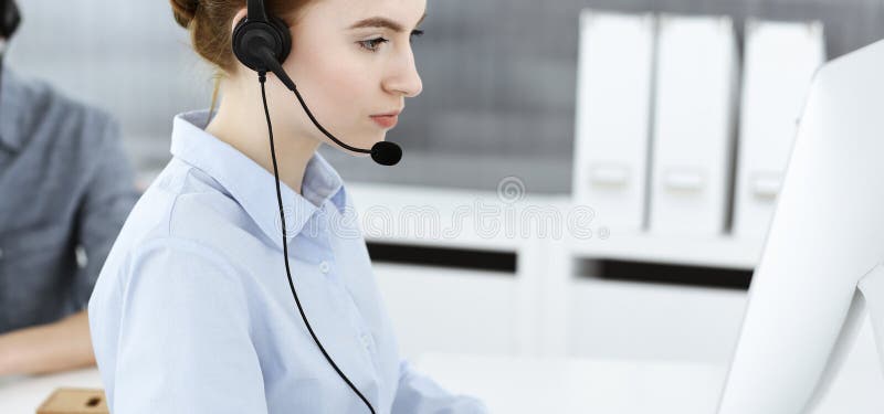 Young Woman Using Headset and Computer while Talking with Customers ...