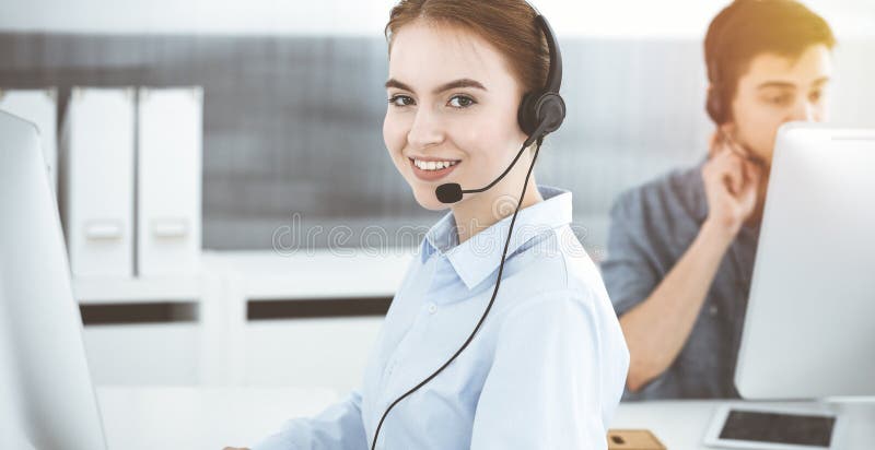 Young Woman Using Headset and Computer while Talking with Customers ...