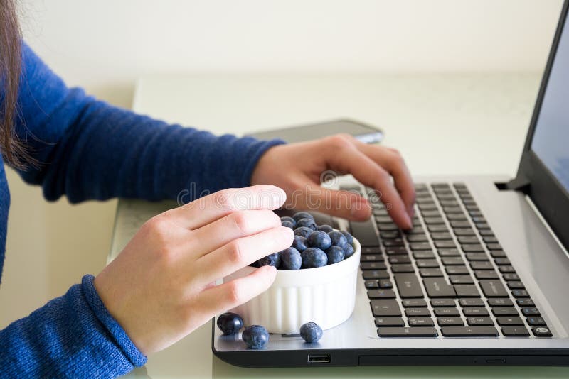 Young Woman Using Laptop Computer at Home and Eating Blueberry Stock ...