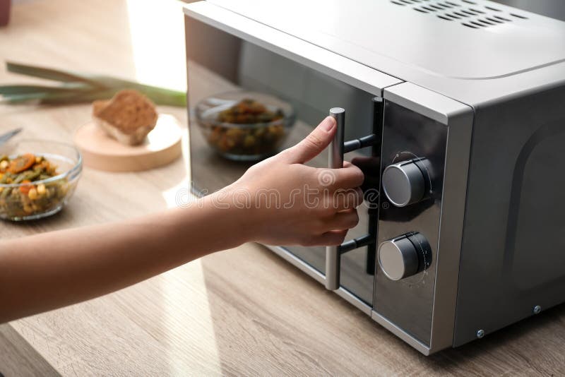 Young Woman Using Microwave Oven on Table Stock Photo - Image of modern ...