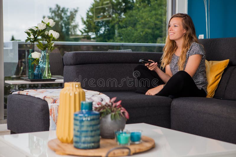 Young Woman Using a Remote Control on the Couch Stock Image - Image of ...