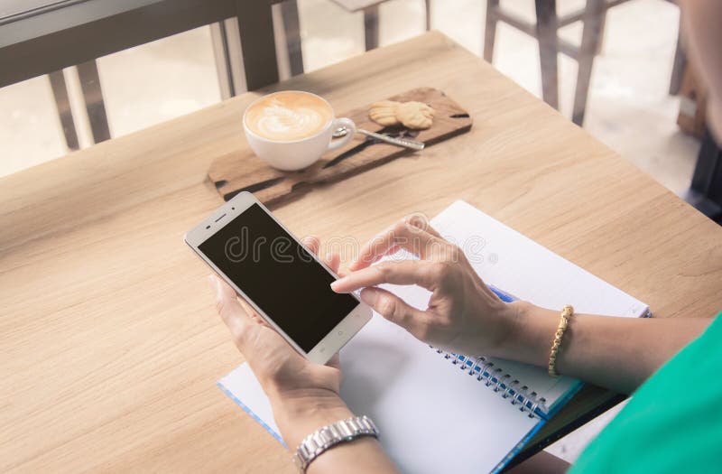 Young Woman Using Smartphone while Taking Notes with Cup of Coffee on ...