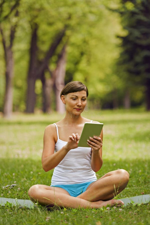 Young Woman Using Tablet Outdoor Siting on Grass. Stock Image - Image ...