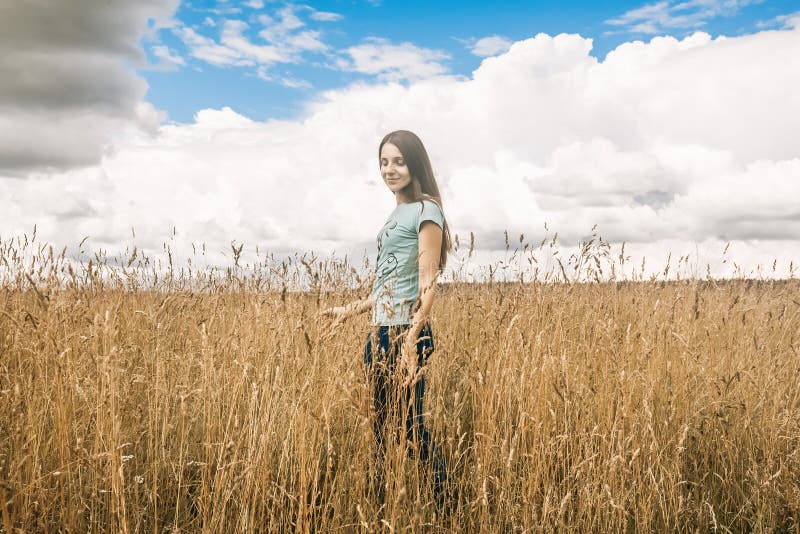 Young Woman Walking on Field. Girl on Meadow with Golden Grass. Nature ... Young Woman Walking on Field. Girl on Meadow with Golden Grass. Nature ...