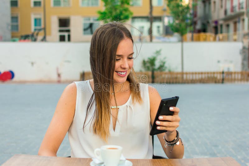 Young Woman is Watching Mobile while she is Having Coffee Stock Photo ...