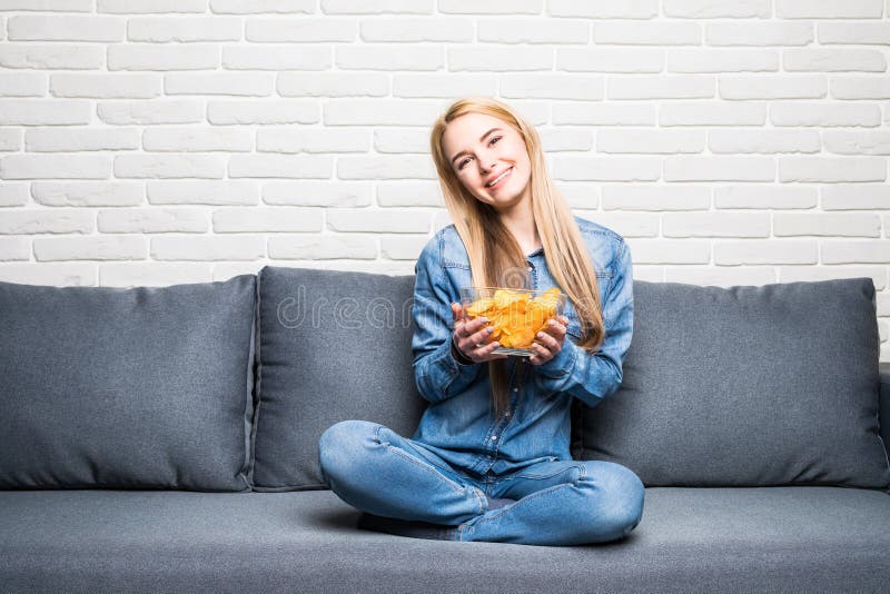 Young Woman Watching TV and Eating Chips on Sofa at Home Stock Image ...