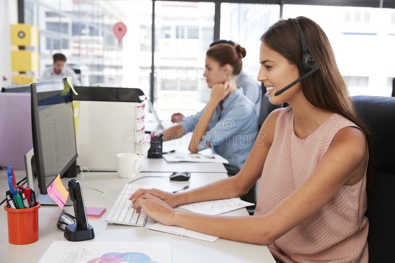 Young Woman Wearing Headset Using Laptop Computer in Office Stock Image ...