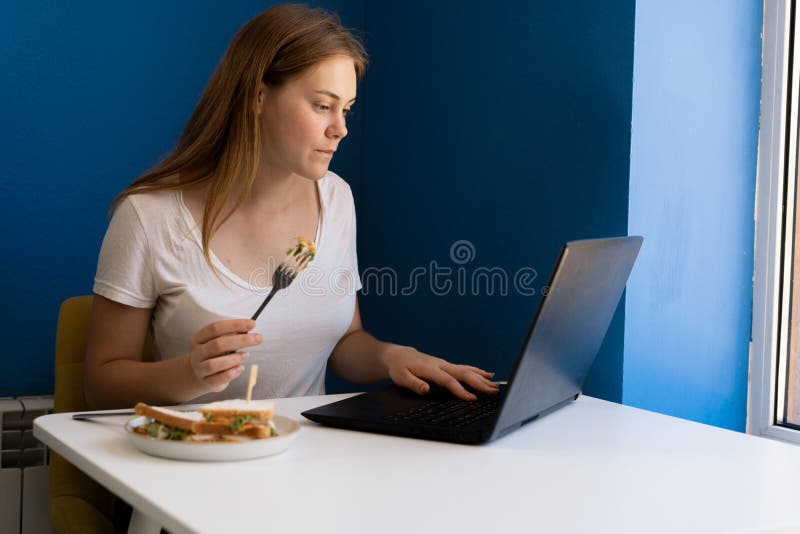Young Woman is Working on the Computer and Having Breakfast at the Cafe ...