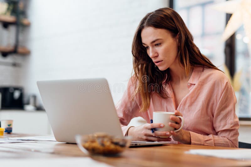 Young Woman Working at Home in the Kitchen with a Laptop while Eating ...