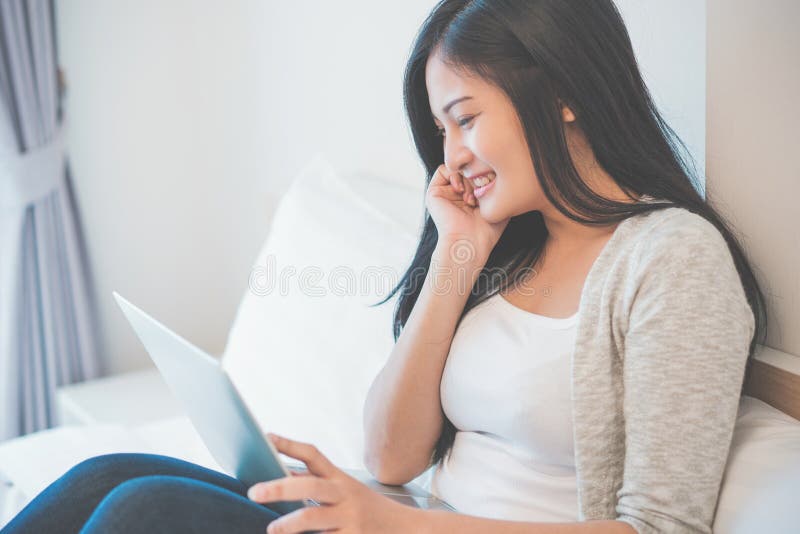 Young Woman Working on a Laptop Sitting on Bed at Home Stock Image ...
