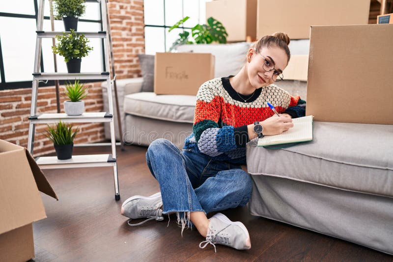 Young Woman Writing on Notebook Sitting on Floor at New Home Stock ...