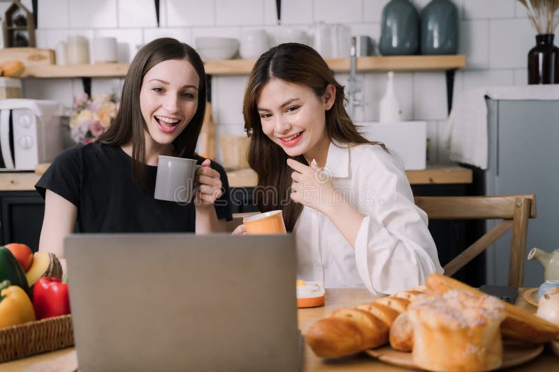 Young Women Enjoy Talking while Drinking Milk in the Kitchen in the ...