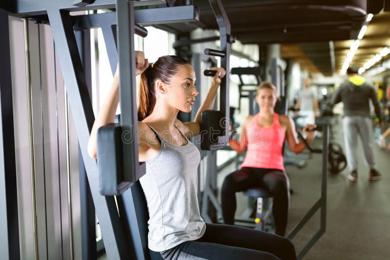 Young Women Exercising on Machine in Gym Stock Image - Image of ...