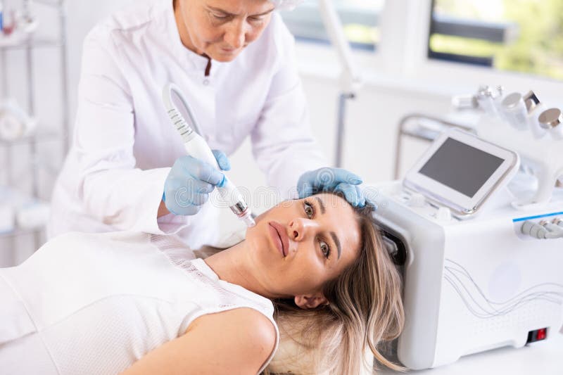 Young Woman Receiving Facial Procedure with Hydrogen and Oxygen Ions ... Young Woman Receiving Facial Procedure with Hydrogen and Oxygen Ions ...