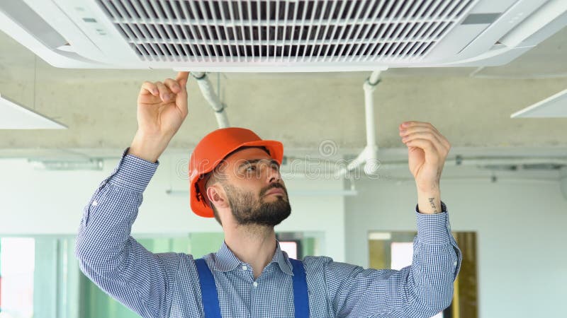 Young Worker Adjusting Air Conditioning System. Air Conditioning ...