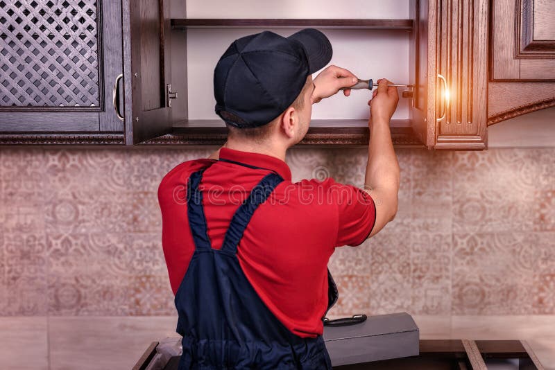 A Young Worker is Assembling Modern Wooden Kitchen Furniture Stock ...