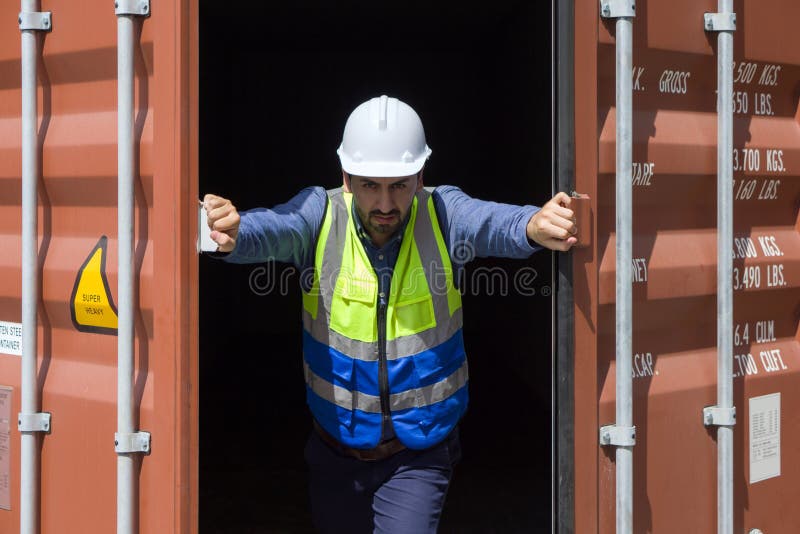 Young Worker with Safety Vest and Yellow Hardhat Pushing Container Door ...