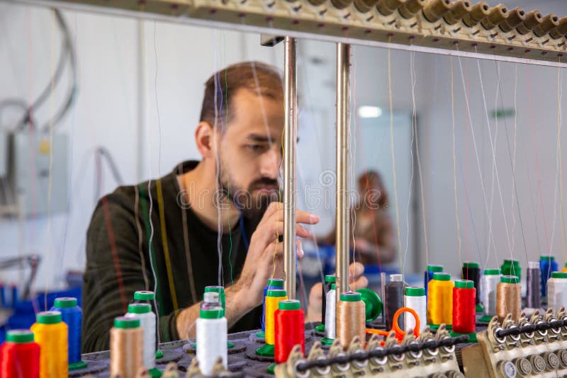 Young Worker from the Sewing Factory that Arranges the Spools of Yarn ...