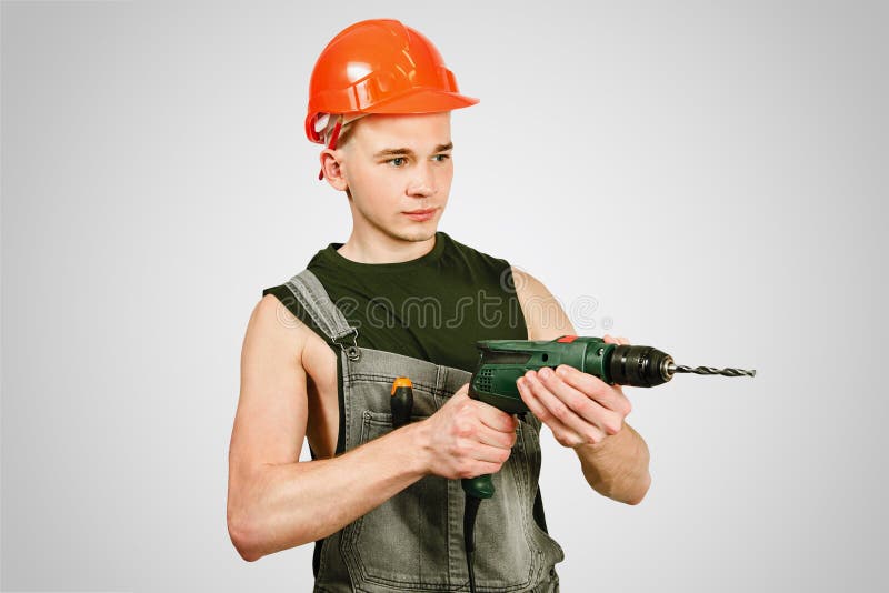 Young Working Guy in Hard Hat Holds Drill on a Gray Background Stock ...