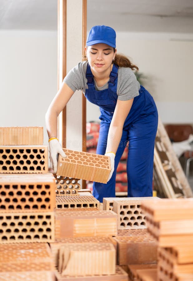 Young Workwoman Stacking Bricks at Construction Site Indoors Stock ...