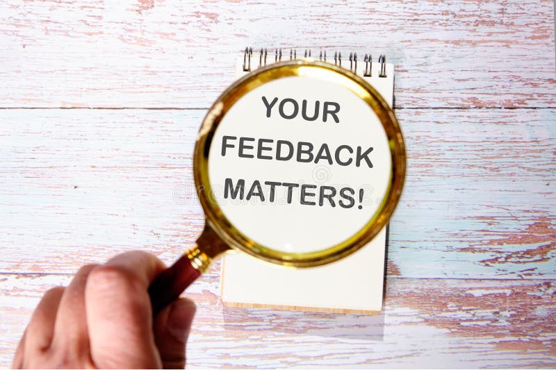 YOUR FEEDBACK MATTERS Text Seen through Magnifying Glasses on a Notepad ...