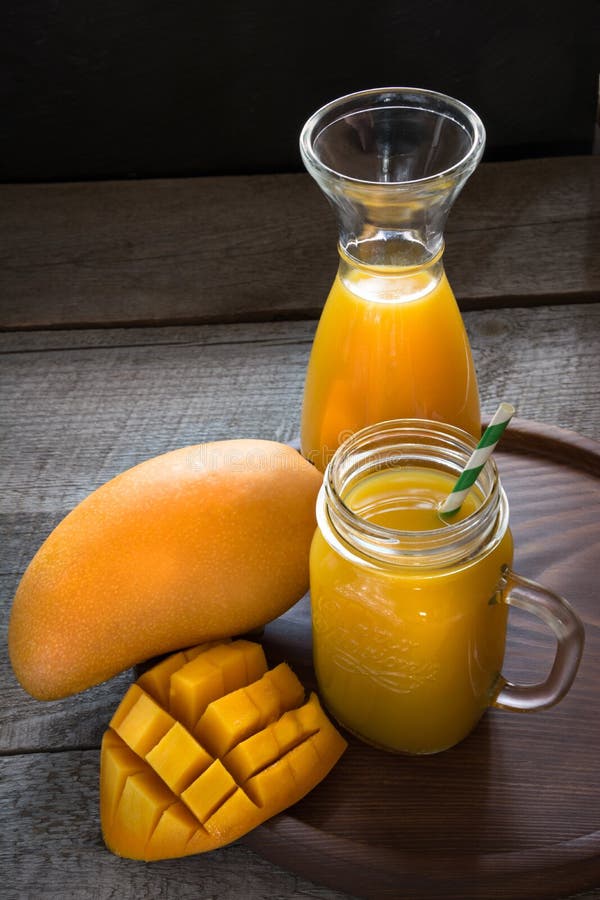 Zumo Del Mango Y De Naranja Y Rebanada De Mango En La Tabla De Madera ...