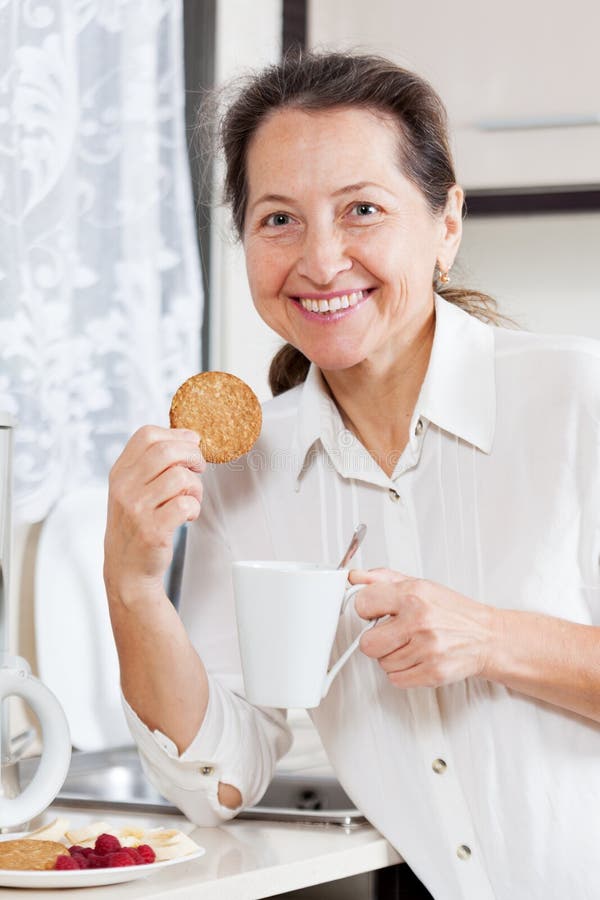 Äldre Kvinna Som äter Frukost I Köket Arkivfoto Bild Av Mormor Moget