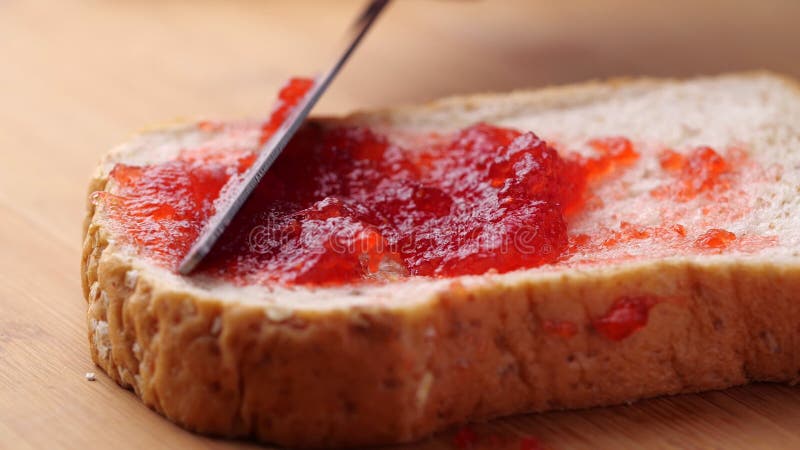 在面包上撒草莓酱 在面包片上涂有刀的草莓酱 以4k慢动作拍摄 股票视频 - 视频 包括有 刀子, 果冻: 179467009