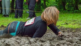 Woman Crawling Through Mud As Part Of Obstacle Course Stock Footage ...