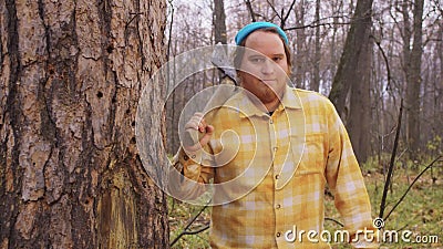 A Bearded Lumberjack Emerges from Behind a Tree with an Axe on His ...