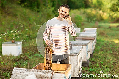 Beekeeper Holding A Honeycomb Full Of Bees. A Man Smiling And Gently ...