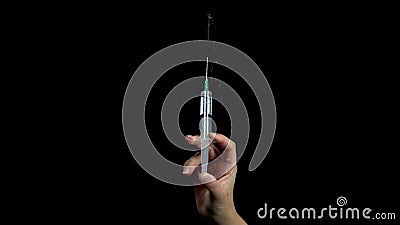 On a Black Background, a Hand Holds a Syringe and Squeezes Out Liquid ...