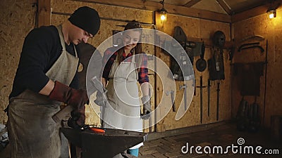 Blacksmith Demonstrates Process of Forging Iron Standing Next To a ...