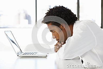 Businessman Sitting At Desk In Office Staring At Laptop Royalty-Free ...