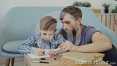 Child is Learning, Writing Words in Exercise Book and His Father is ...