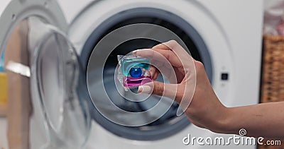 Close-up of Hands Holding a Laundry Capsule and Dropping it into the ...