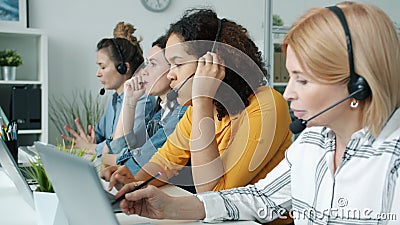 Diverse Group of Women Making Calls Using Headsets and Laptops Working ...