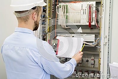 Engineer In White Helmet Reads Design Drawing Against Electric ...