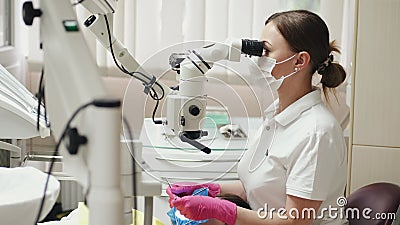 A Female Endodontist is Treating Canals Under the Microscope. Stock ...