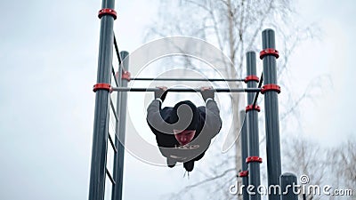 The Guy is Hanging on a Horizontal Bar with His Hands Behind His Back ...