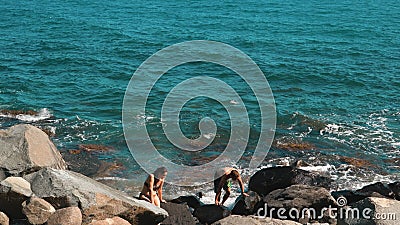 A Guy Sneaking Around on Slippery Rocks Next To a Girl in a Bathing ...