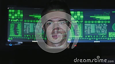 Hacker Programmer Working on a Computer while Green Code Characters Reflect on His Face in a ...