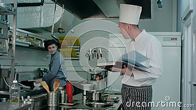Head Chef Looking for Recipe in a Book while Checking upon His Cook ...