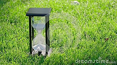 An Hourglass with Spilling Sand Standing on Green Grass with Glittering ...