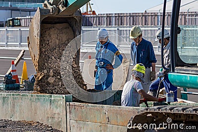Group Of Japanese Constructors Working On The Street Using An Excavator ...
