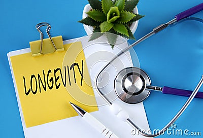 LONGEVITY - Word On A Yellow Notebook On A Blue Background With A ...