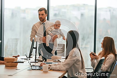 Man With His Son. Infant Baby Is In The Office Where Group Of People ...