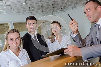 Man At Reception Desk With Young Staff Pointing Left Royalty-Free Stock ...