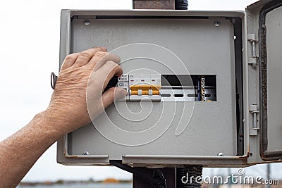 A Man Switches The Toggle Switches Of The Electrical Panel On The Pole ...