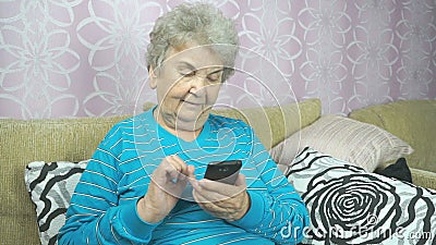 Old Lady Using a Mobile Phone Sits on a Beige Sofa Stock Footage ...